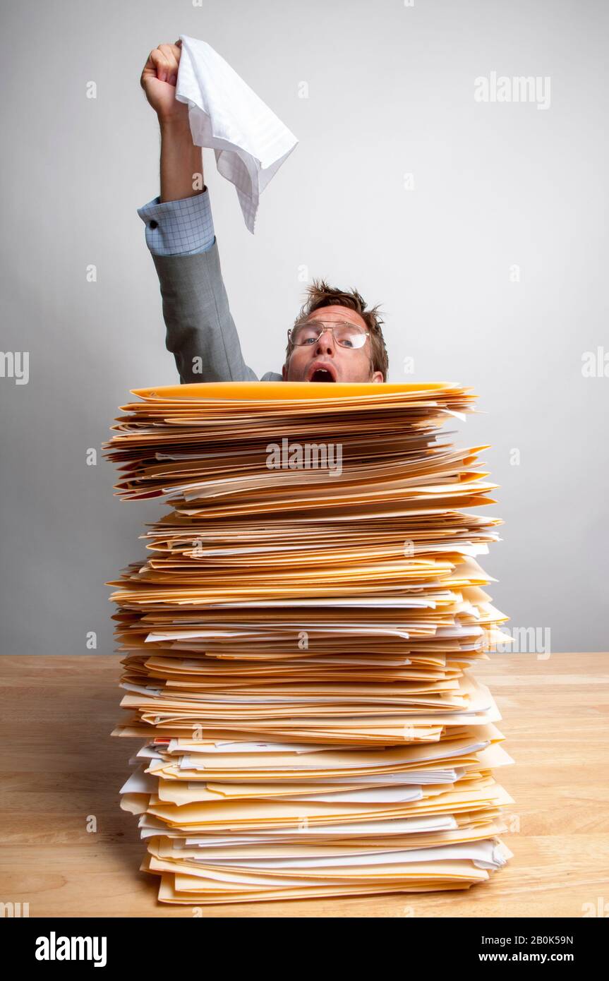 Overworked businessman sitting at his desk waving a white flag of ...