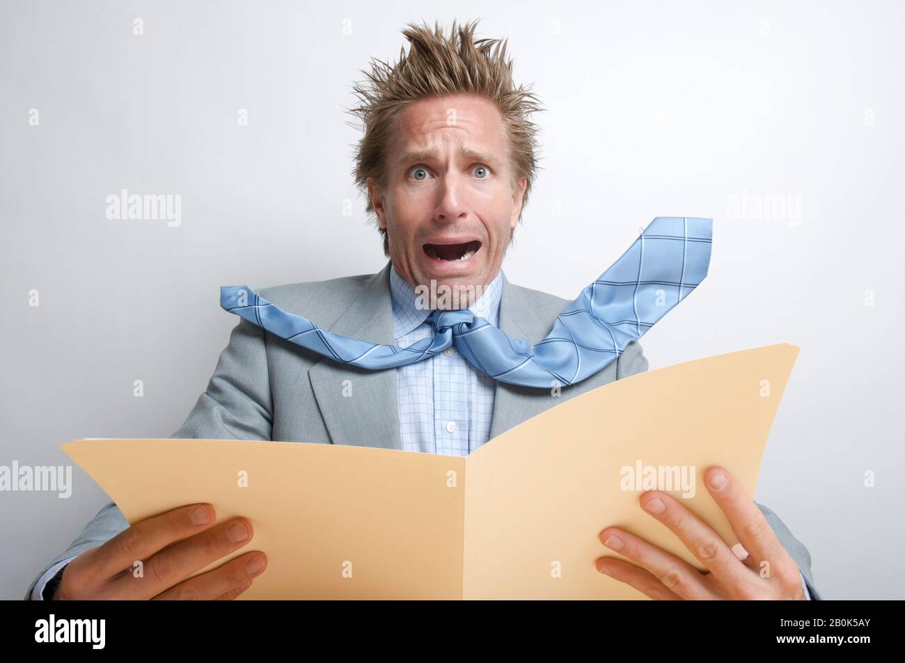 Upset businessman reacting to the contents of a file folder Stock Photo ...
