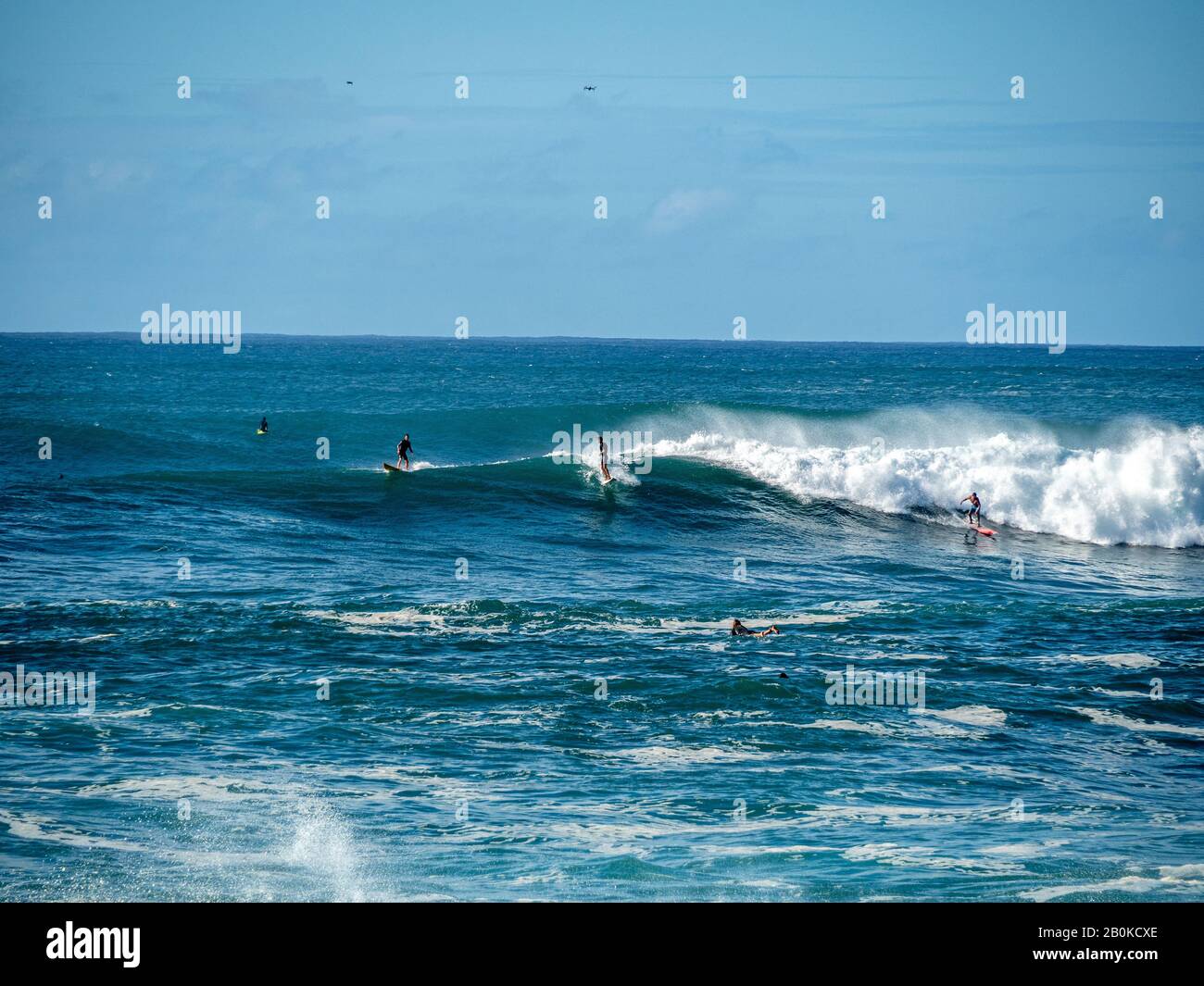 Surfers enjoying big waves on the north shore of Oahu with aquamarine ...
