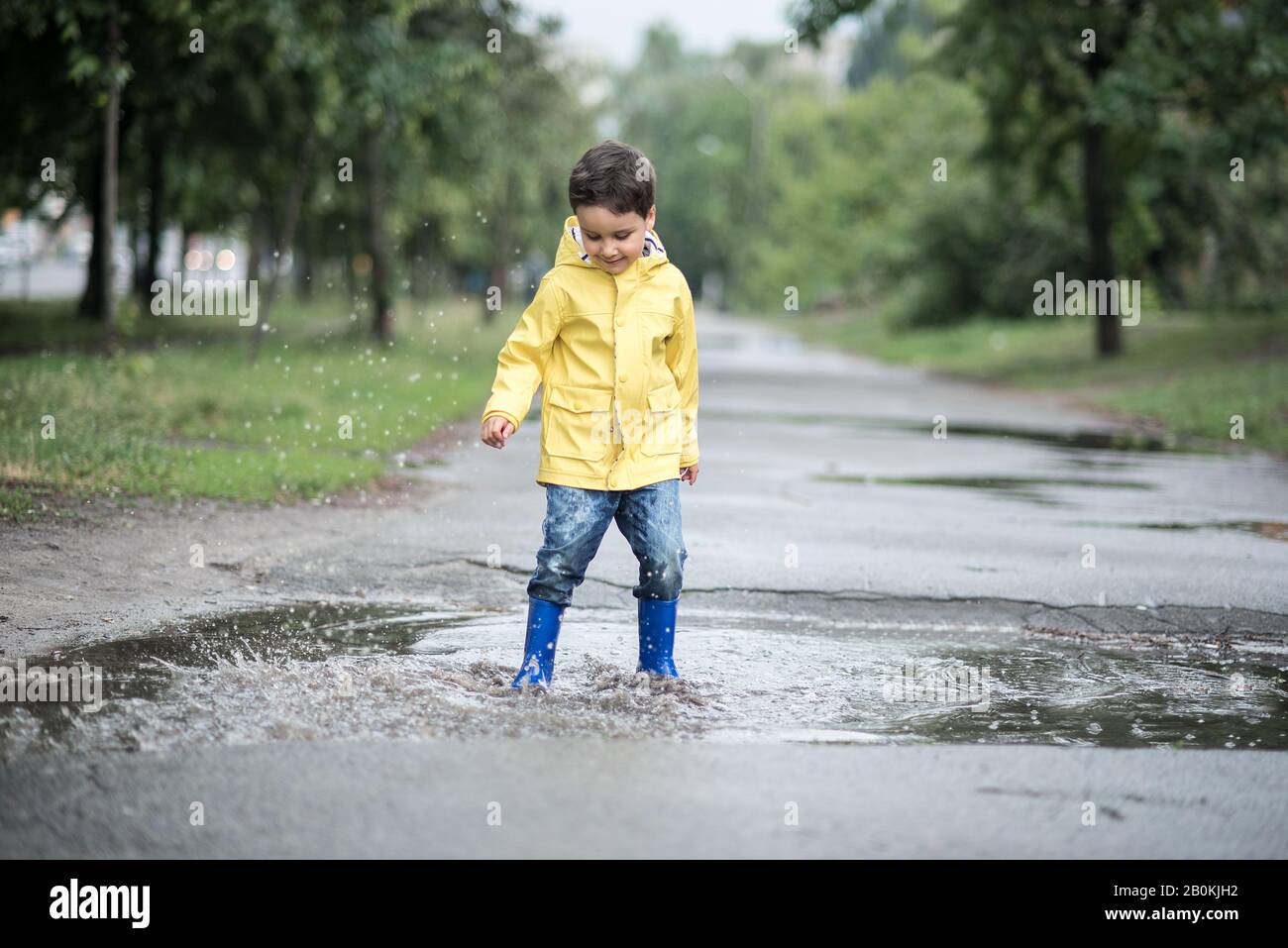 A wet child is jumping in a puddle. Fun on the street. Tempering in ...