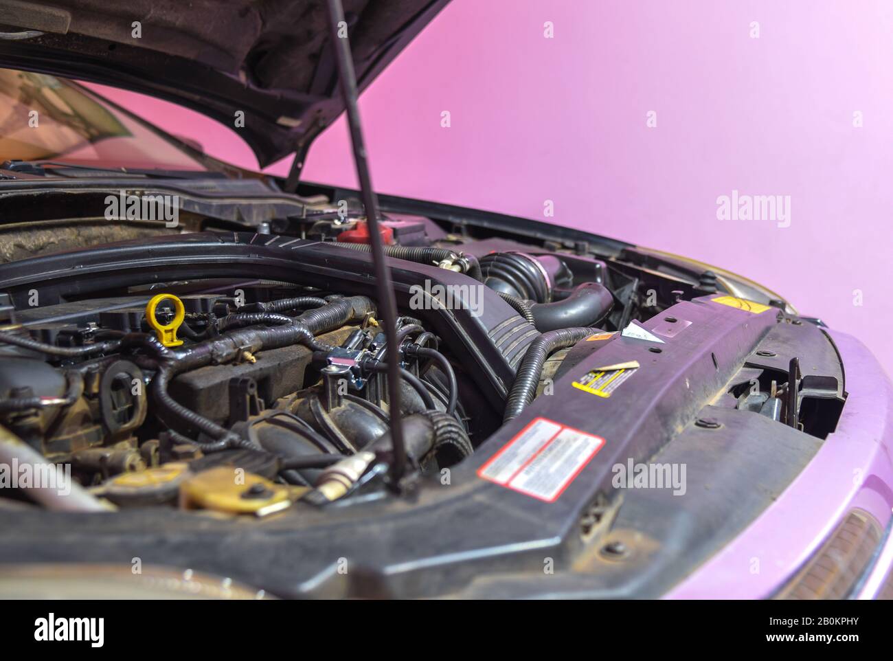 A car stopped in the garage with the hood open and the engine showing ...