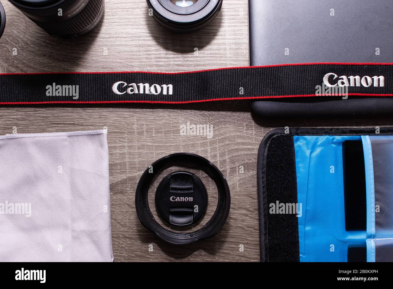 Photography flat lay on a grey wood table. Canon black strap with red ...