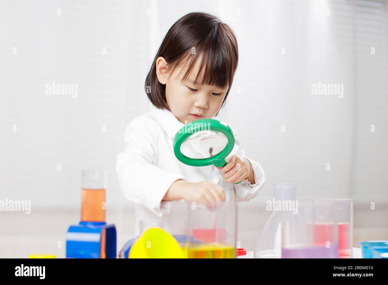toddler girl pretend play scientist role at home against white ...