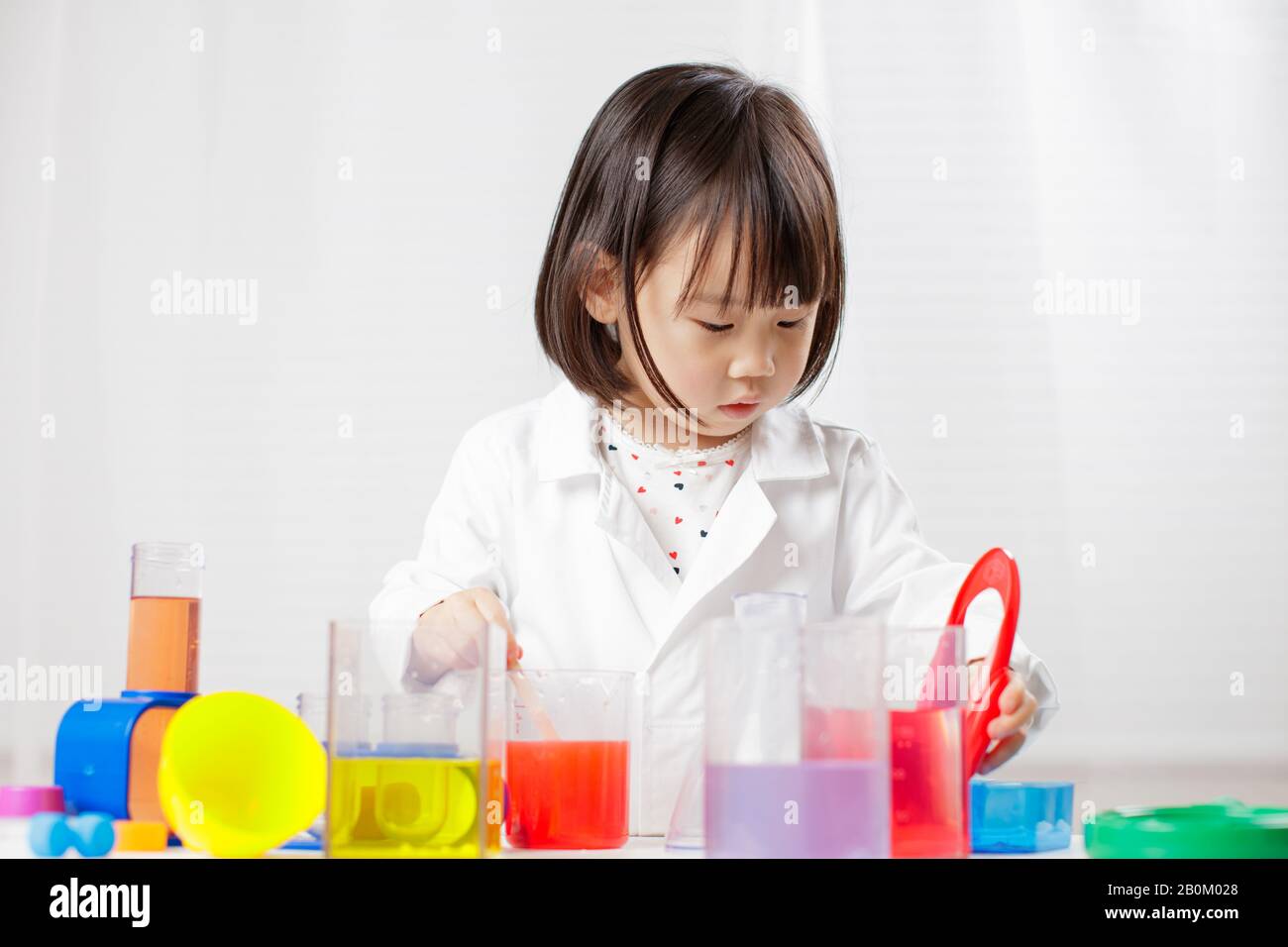 toddler girl pretend play scientist role at home against white ...