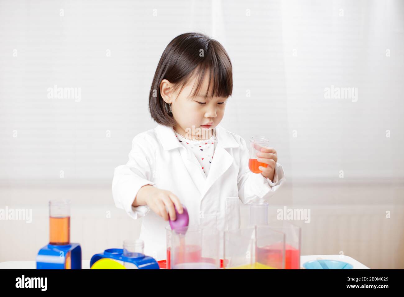toddler girl pretend play scientist role at home against white ...