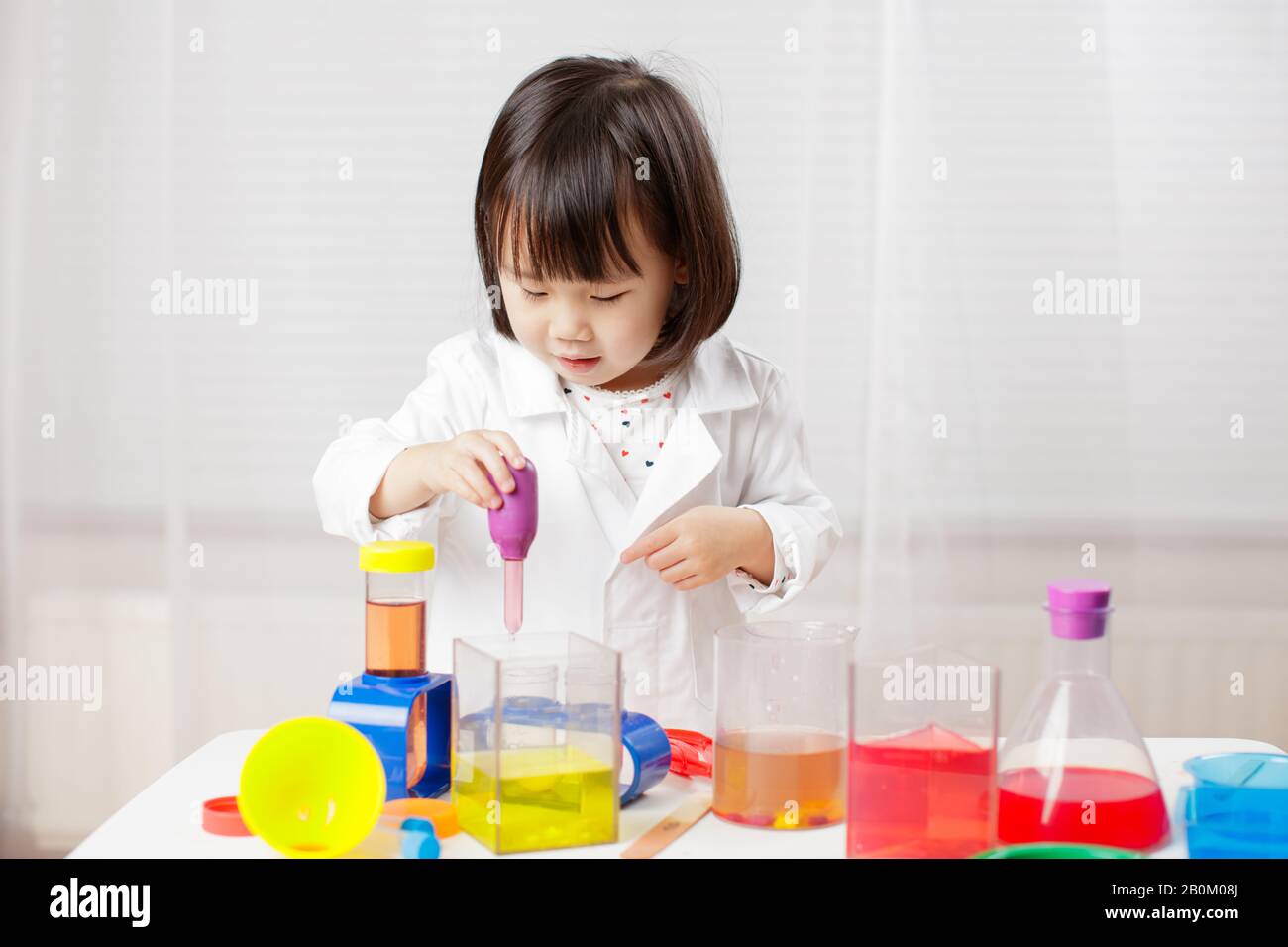 toddler girl pretend play scientist role at home against white ...