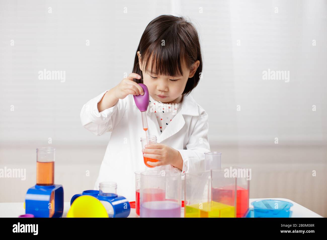 toddler girl pretend play scientist role at home against white ...