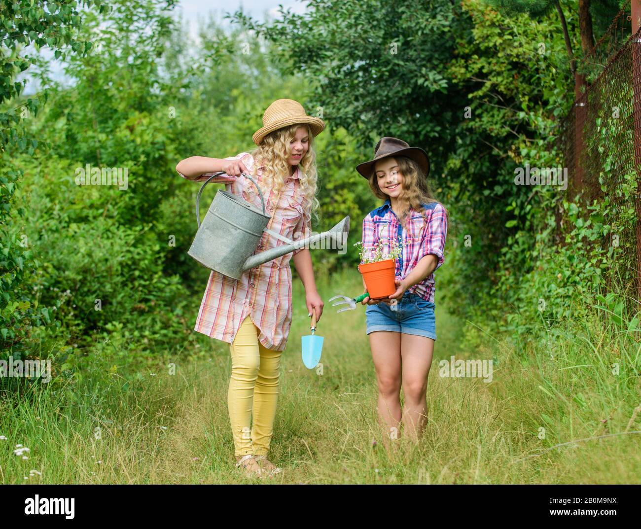 Girls in hats planting plants. Rustic children nature background ...
