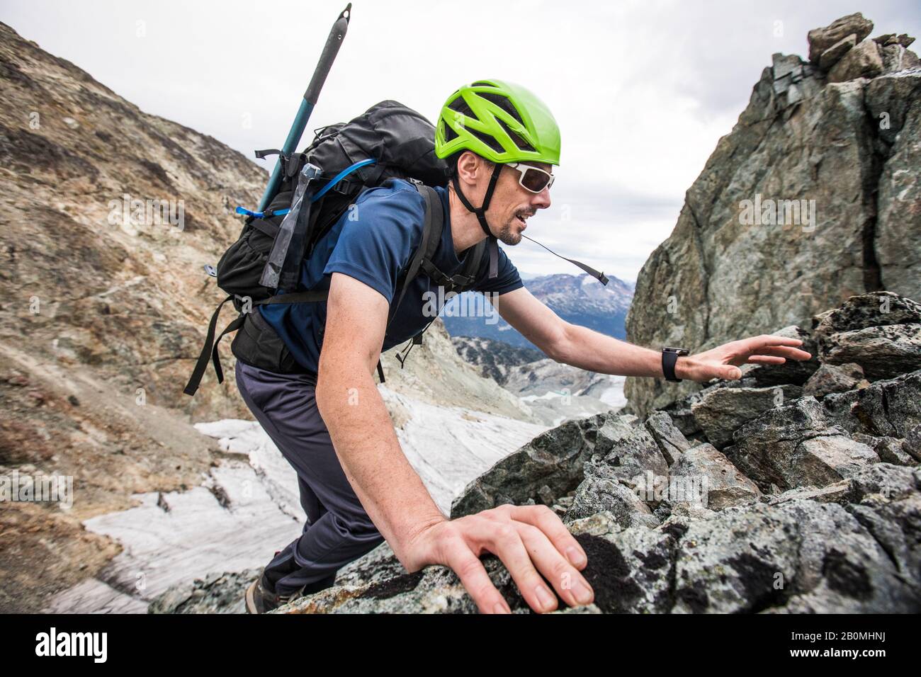 Side view of backpacker climbing over rocky terrain Stock Photo - Alamy