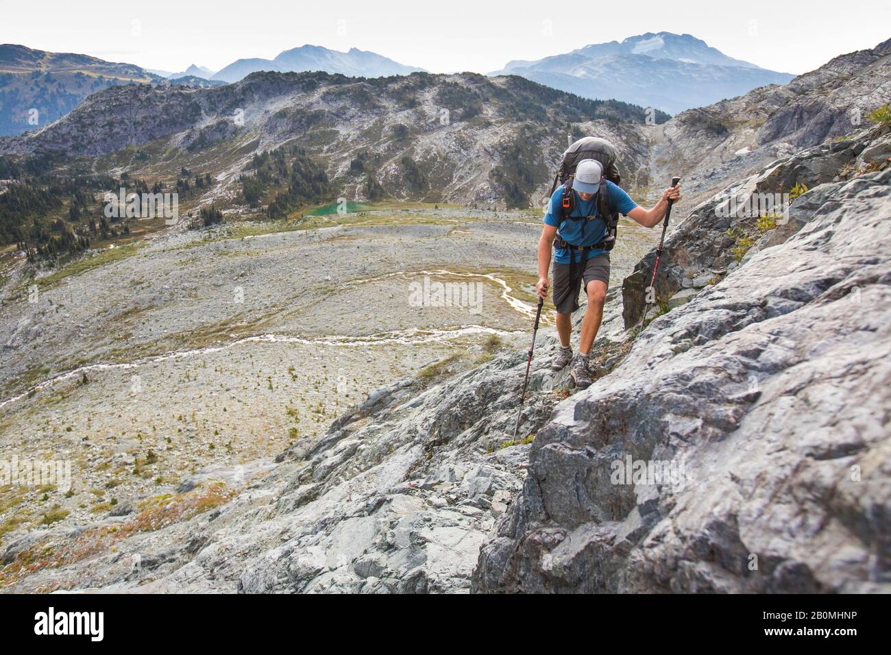 Backpacker hikes across talus slope in mountains near Whistler Stock ...