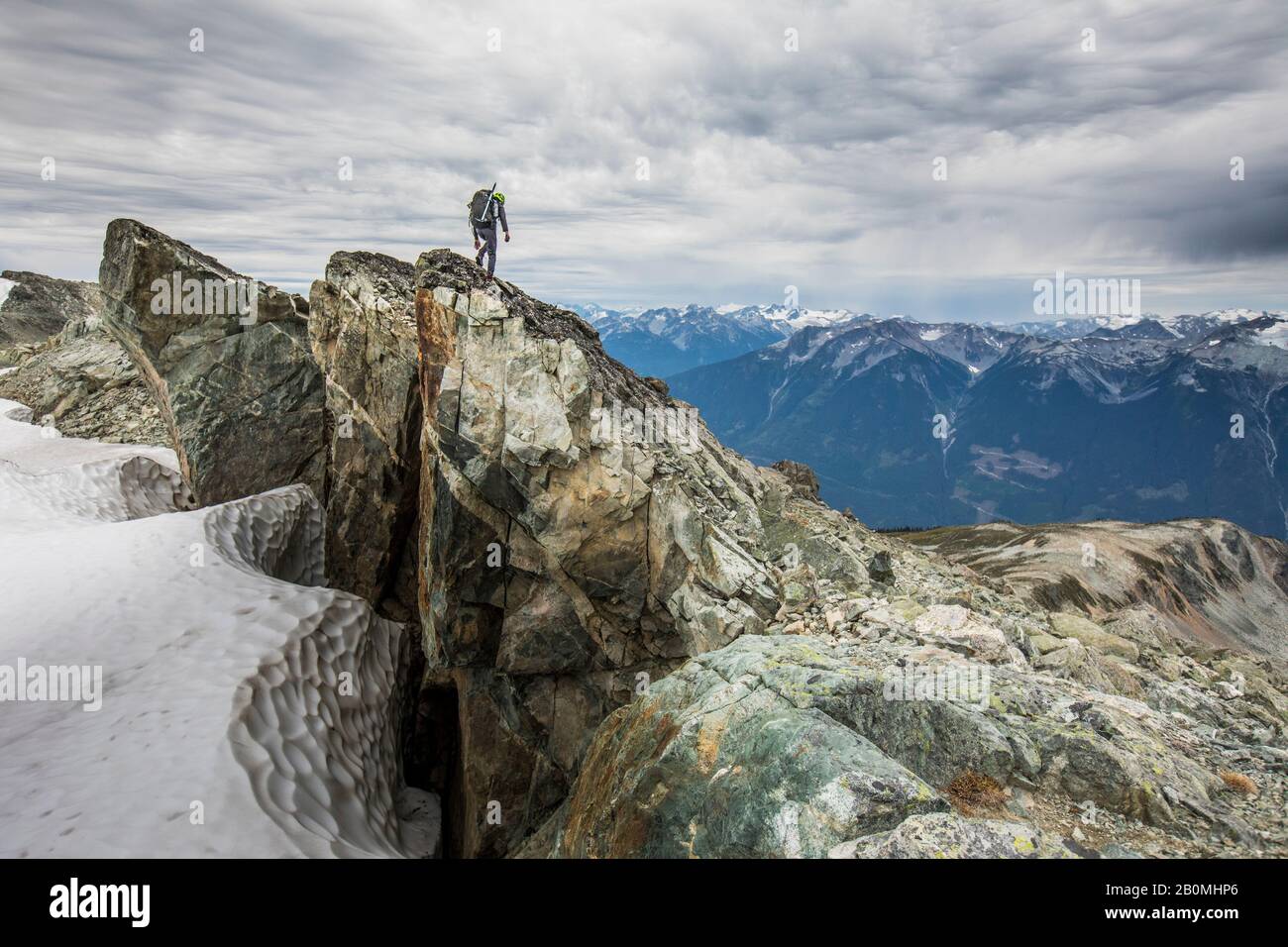 Rear view of climber standing on rocky summit ridge Stock Photo - Alamy