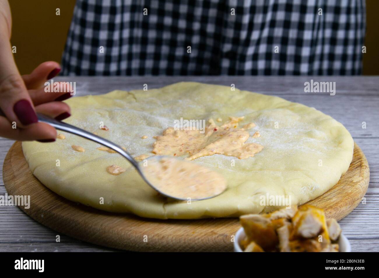 Women's hand smears sauce on pizza. Fresh original italian raw pizza ...