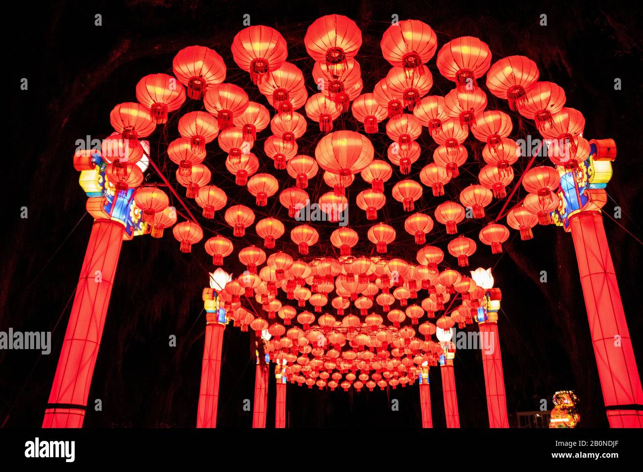 A series of red Chinese lanterns at night and illuminated arranged in a ...