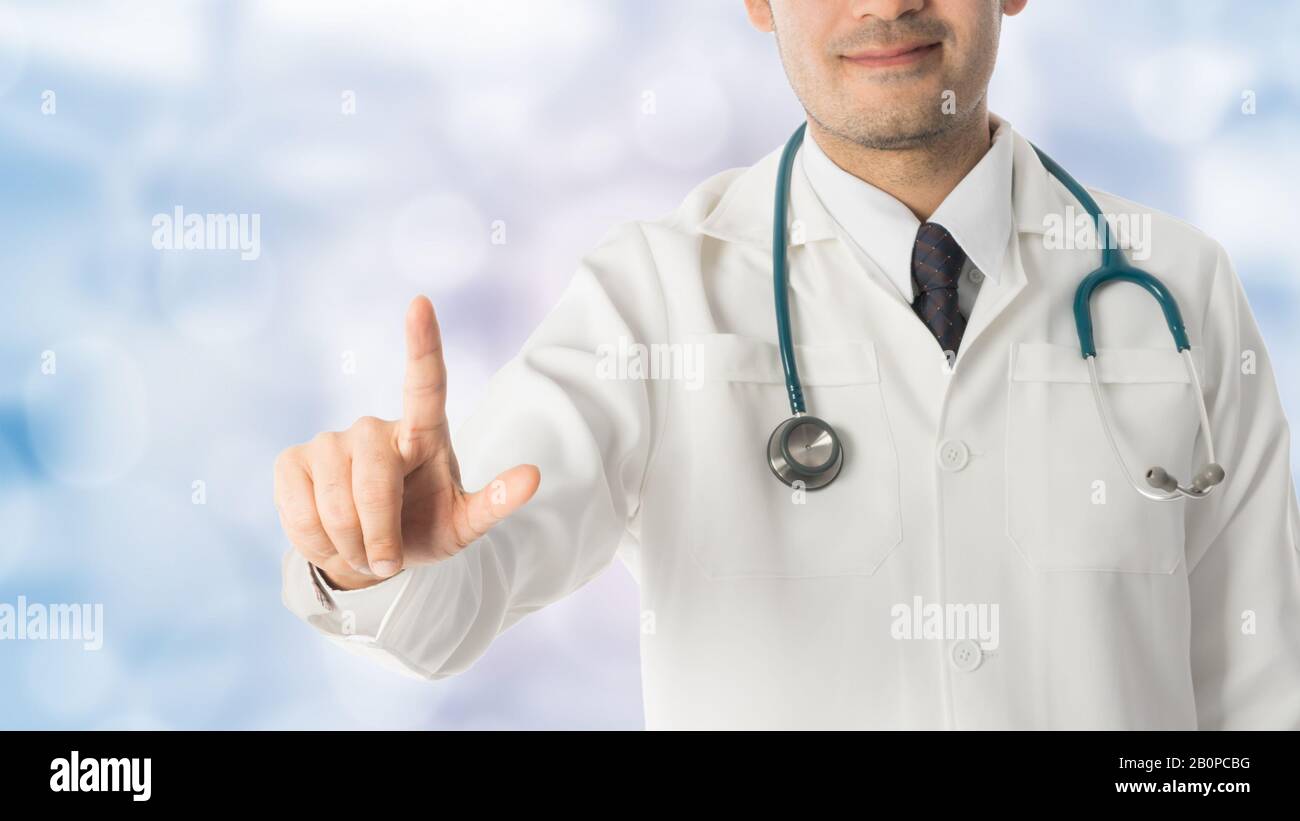 Male doctor pointing finger at copy space, standing in hospital ...