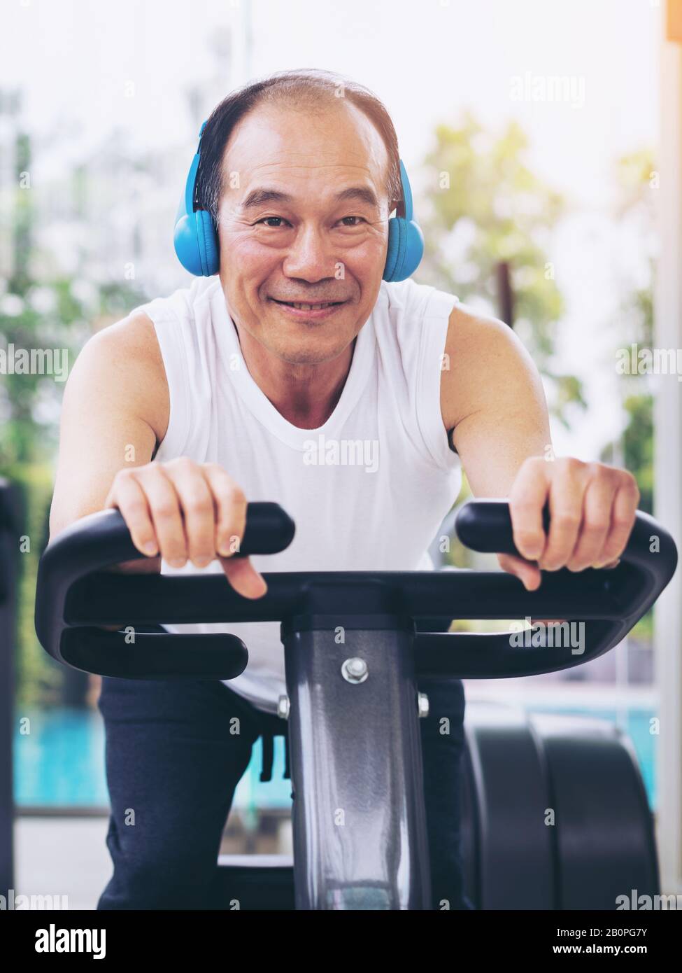 Senior man exercise on cycling machine in fitness center. Mature ...