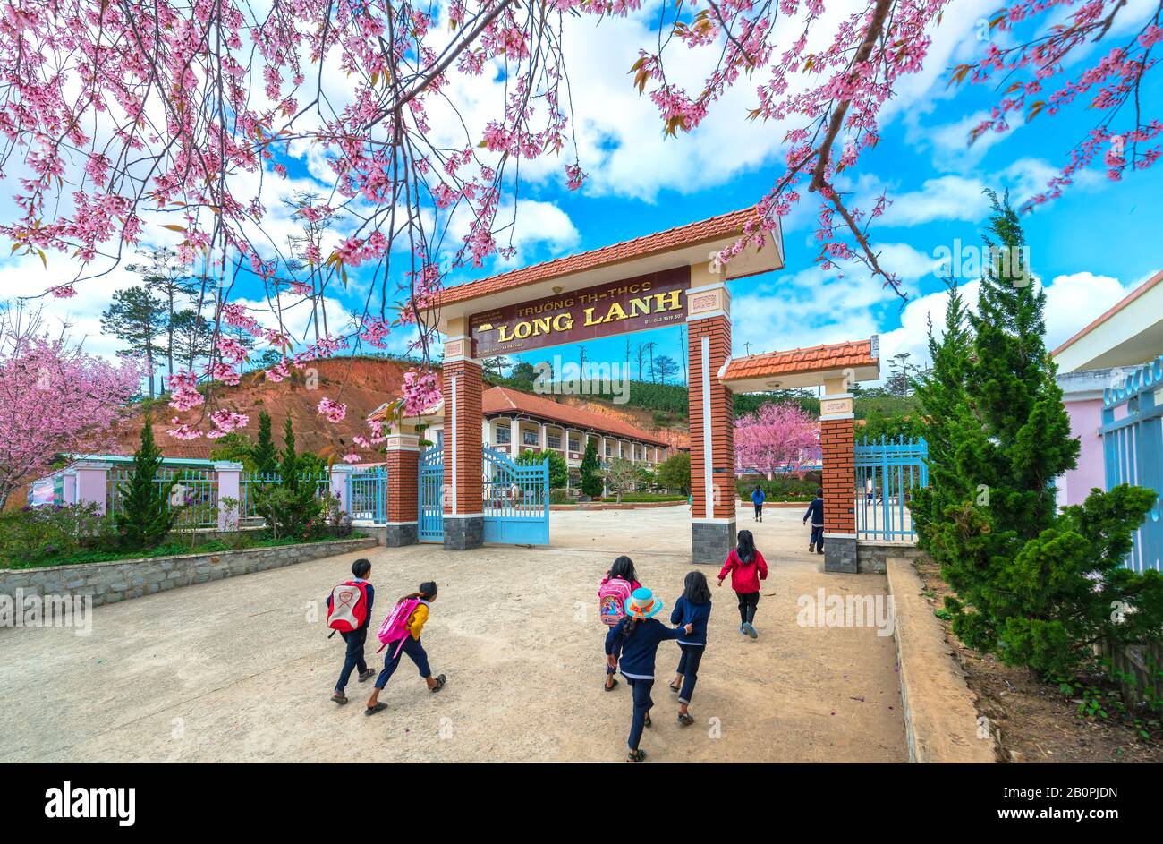 Elementary students in uniform are walking into school gate with a ...