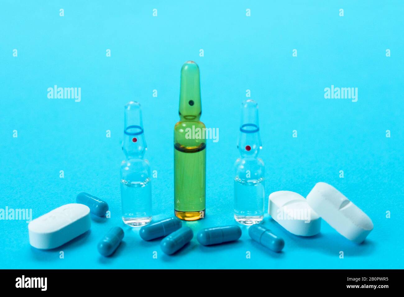 Ampoules for injection and many capsules on a light blue background ...