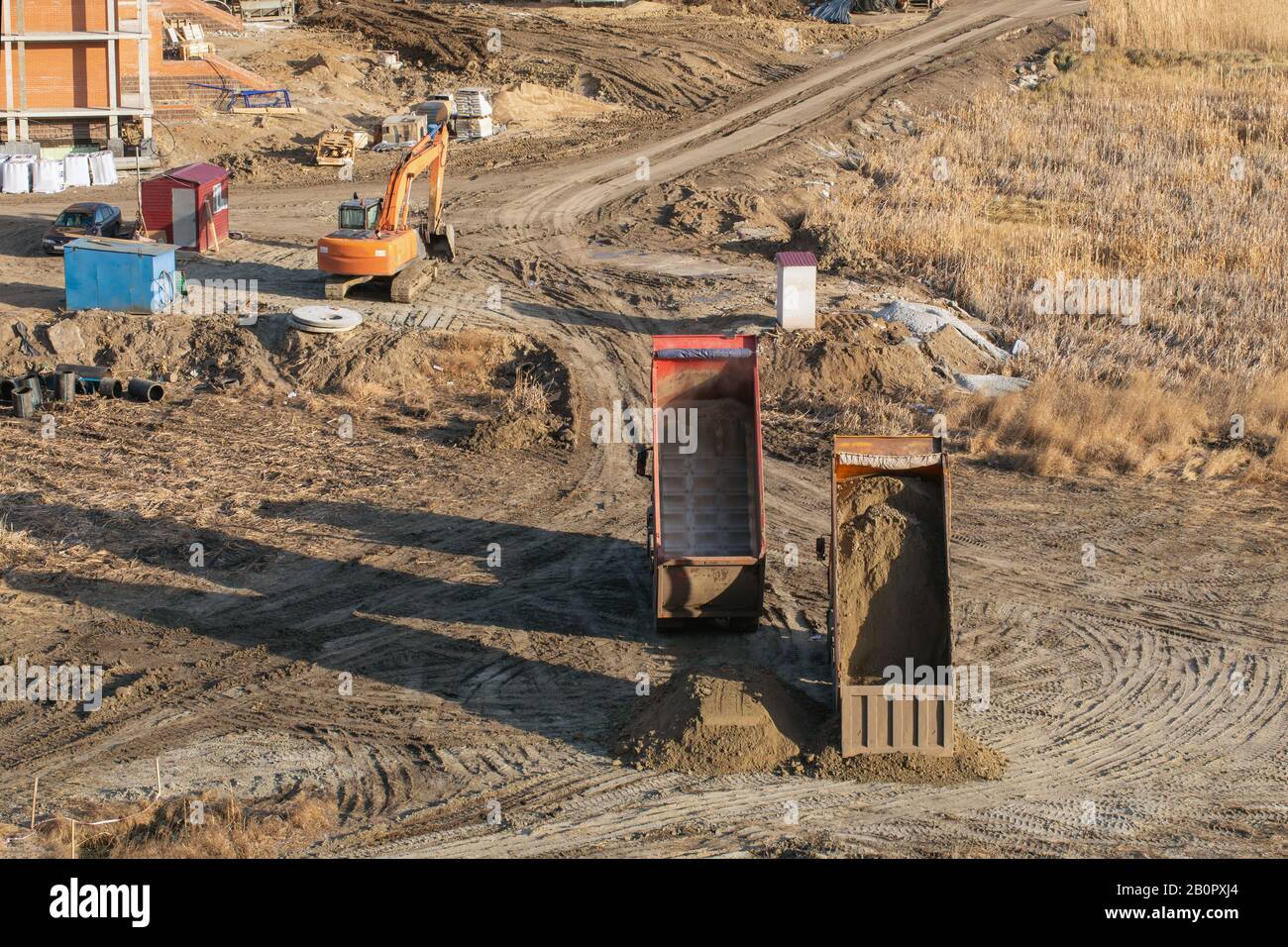 Dump truck unloading process. Dumper trucks unloading earth material or ...