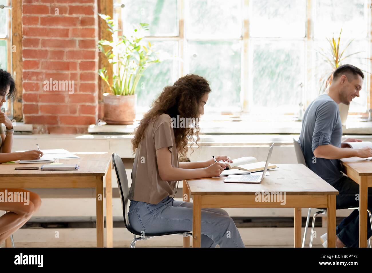 Diverse university college undergraduate students sitting at desks in ...