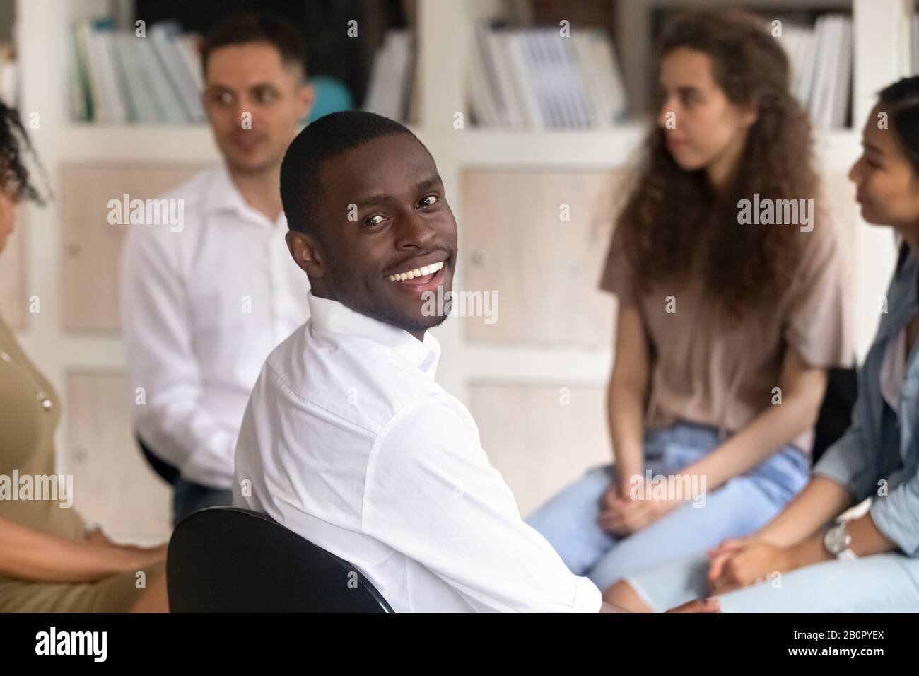 Head shot portrait of smiling African American man sitting at group ...