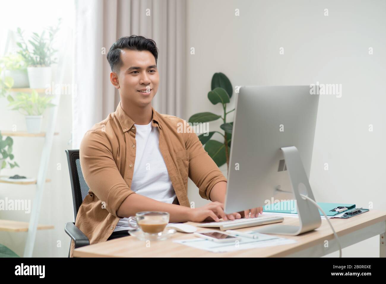 Happy Asian freelancer man is working on his computer Stock Photo - Alamy