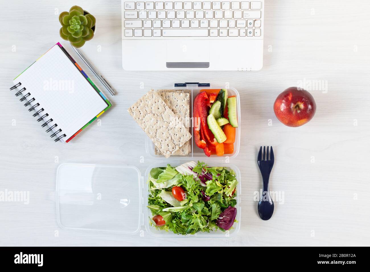 Vegetables and fresh green salad in lunch box on working desk with ...