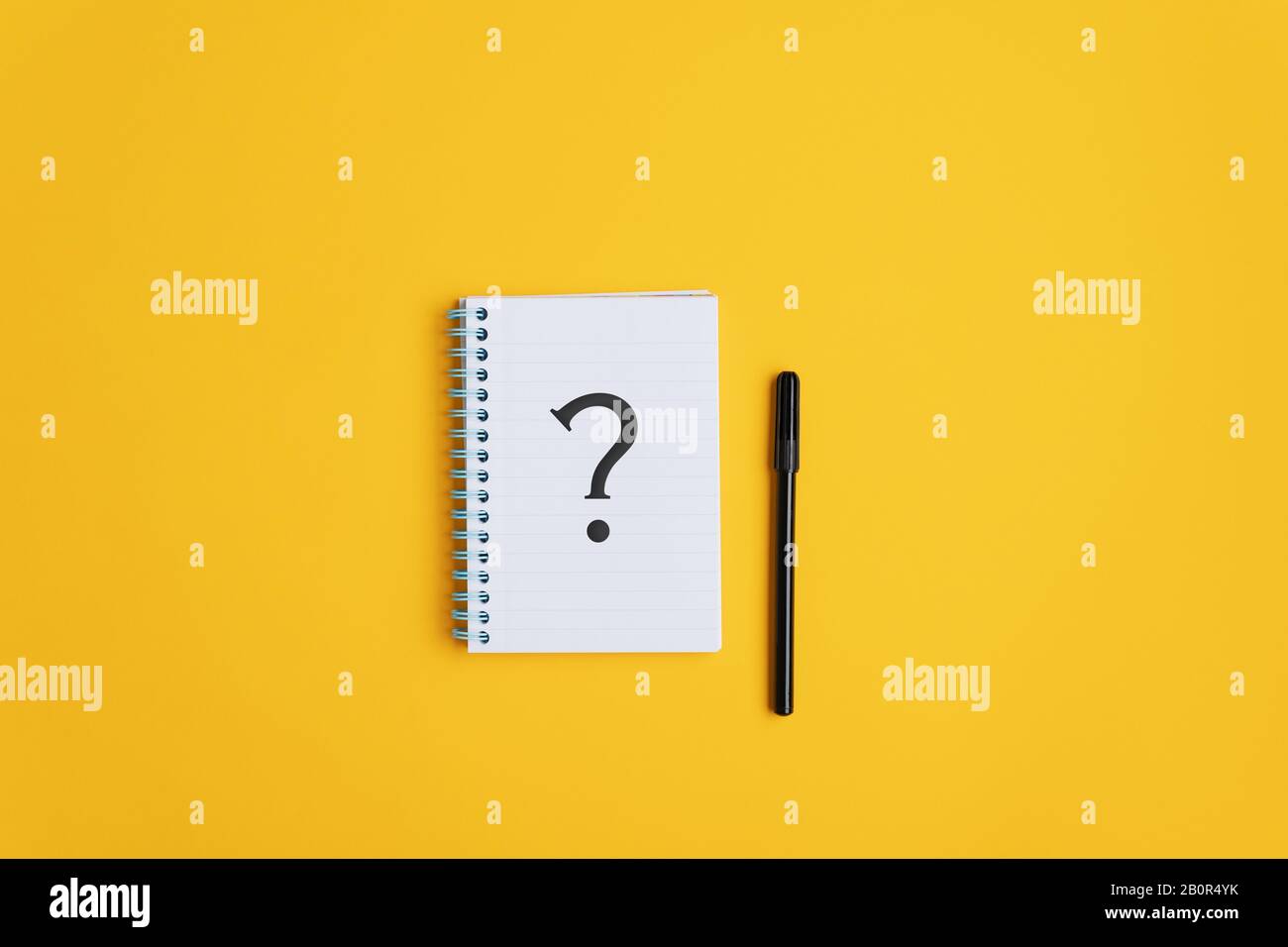 Question mark drawn on notepad with black marker lying next to it. Over ...
