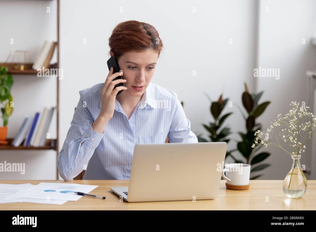 Busy businesswoman talking on phone, using laptop, looking at screen ...