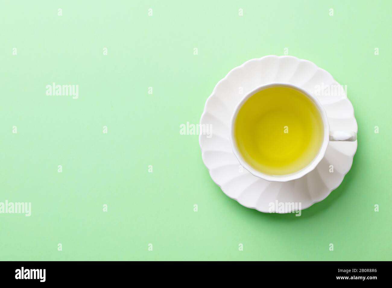 Green tea in a white cup on pastel green background. Top view. Copy ...