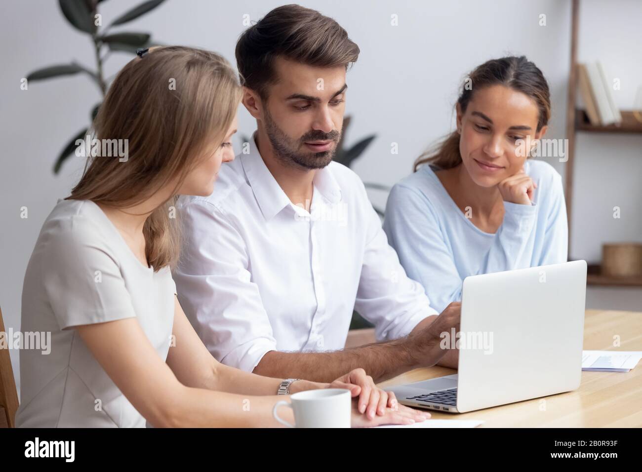 Confident businessman, mentor helping female trainees with new software ...