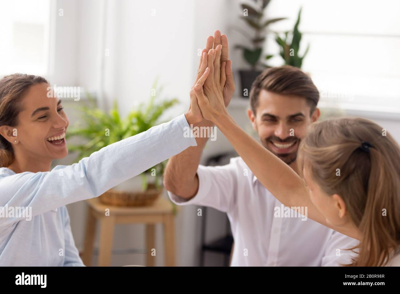 Close up excited employees giving high five after successful ... Close up excited employees giving high five after successful ...