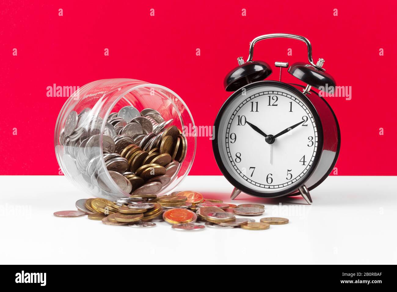 Alarm clock and money coins on the table Stock Photo - Alamy