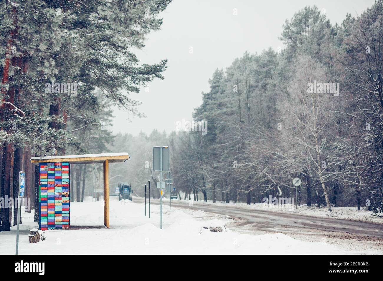 empty bus stop on cold winter afternoon, snowy road in Riga district ...