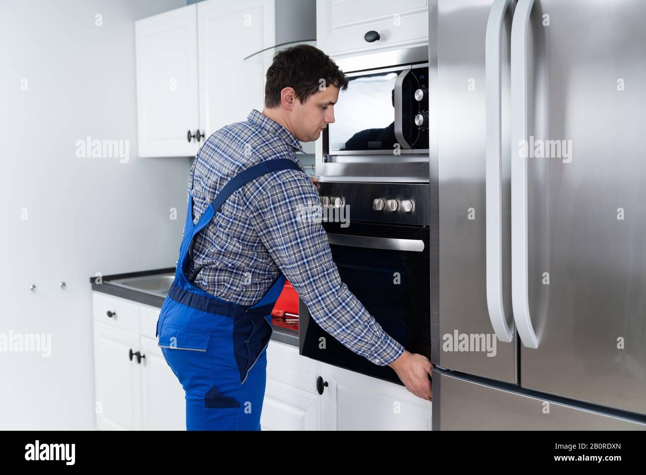 Male Technician In Overall Installing Oven In Kitchen Stock Photo - Alamy
