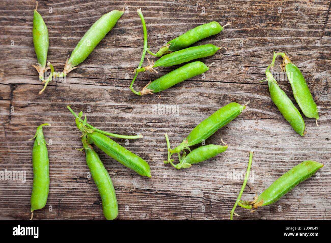 Pea pods on a wooden background Stock Photo - Alamy