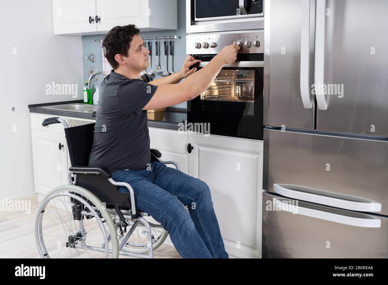 Disabled Man Using Microwave Oven For Baking In Kitchen Stock Photo - Alamy