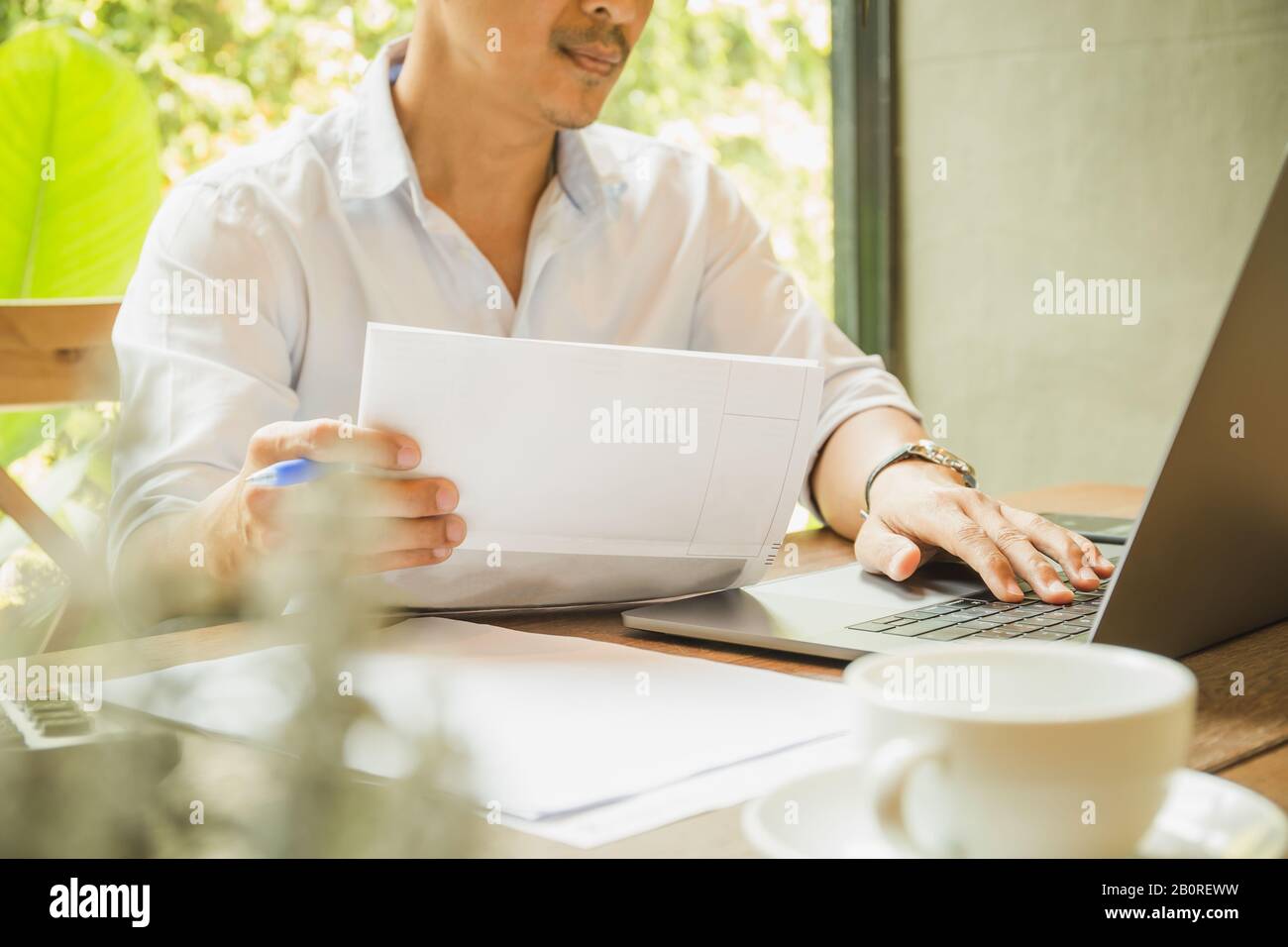 Businessman working with laptop and holding paperwork and documents in ...