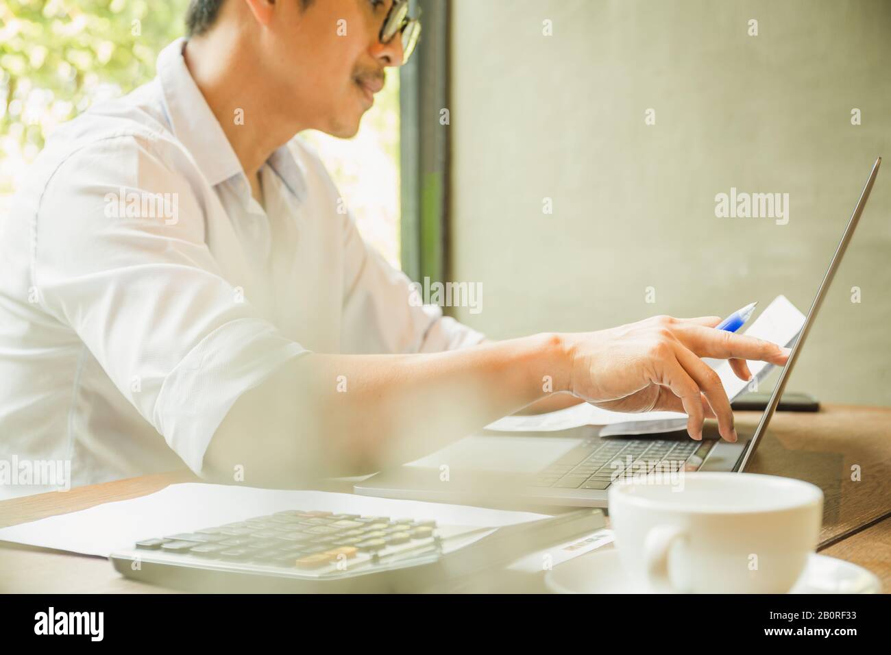 Businessman reading paperwork documents with hand pointing on laptop ...