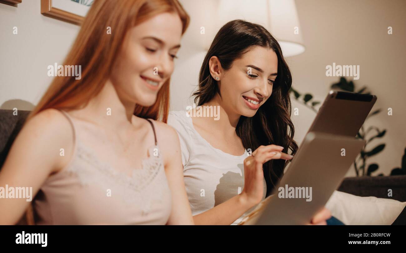 Two beautiful caucasian ladies are using their gadgets while smiling ...