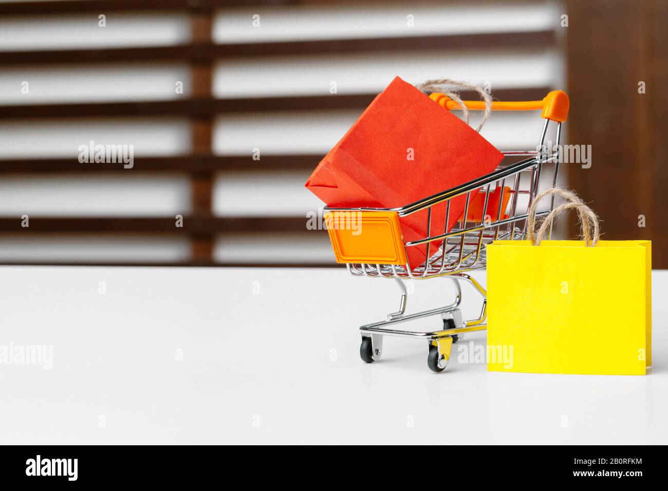 Small shopping cart with paper bags. creative photo Stock Photo - Alamy