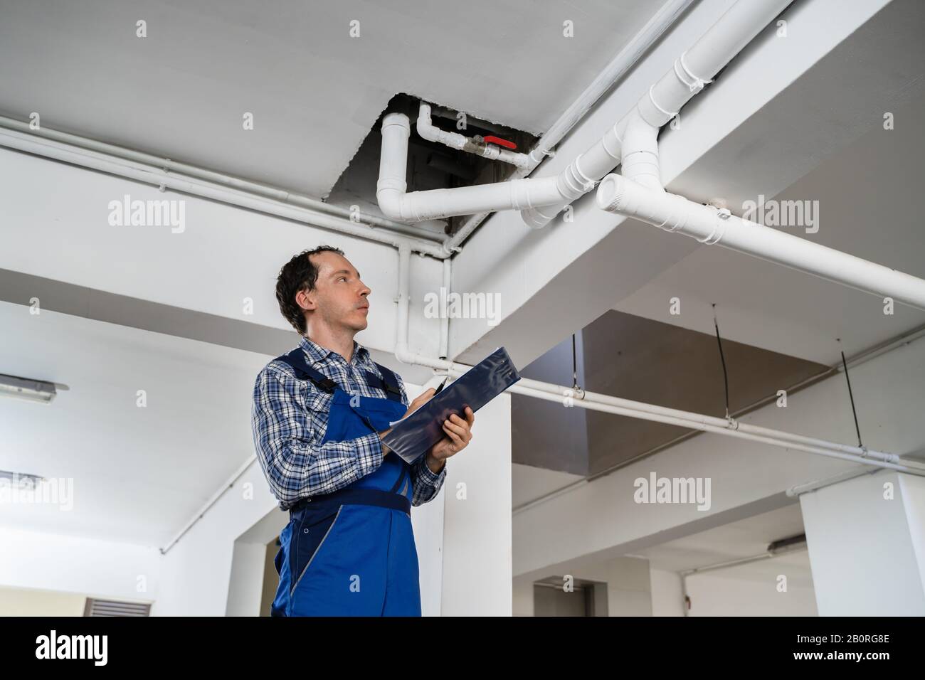 Male Worker Inspecting Pipes In Residential Building Stock Photo - Alamy
