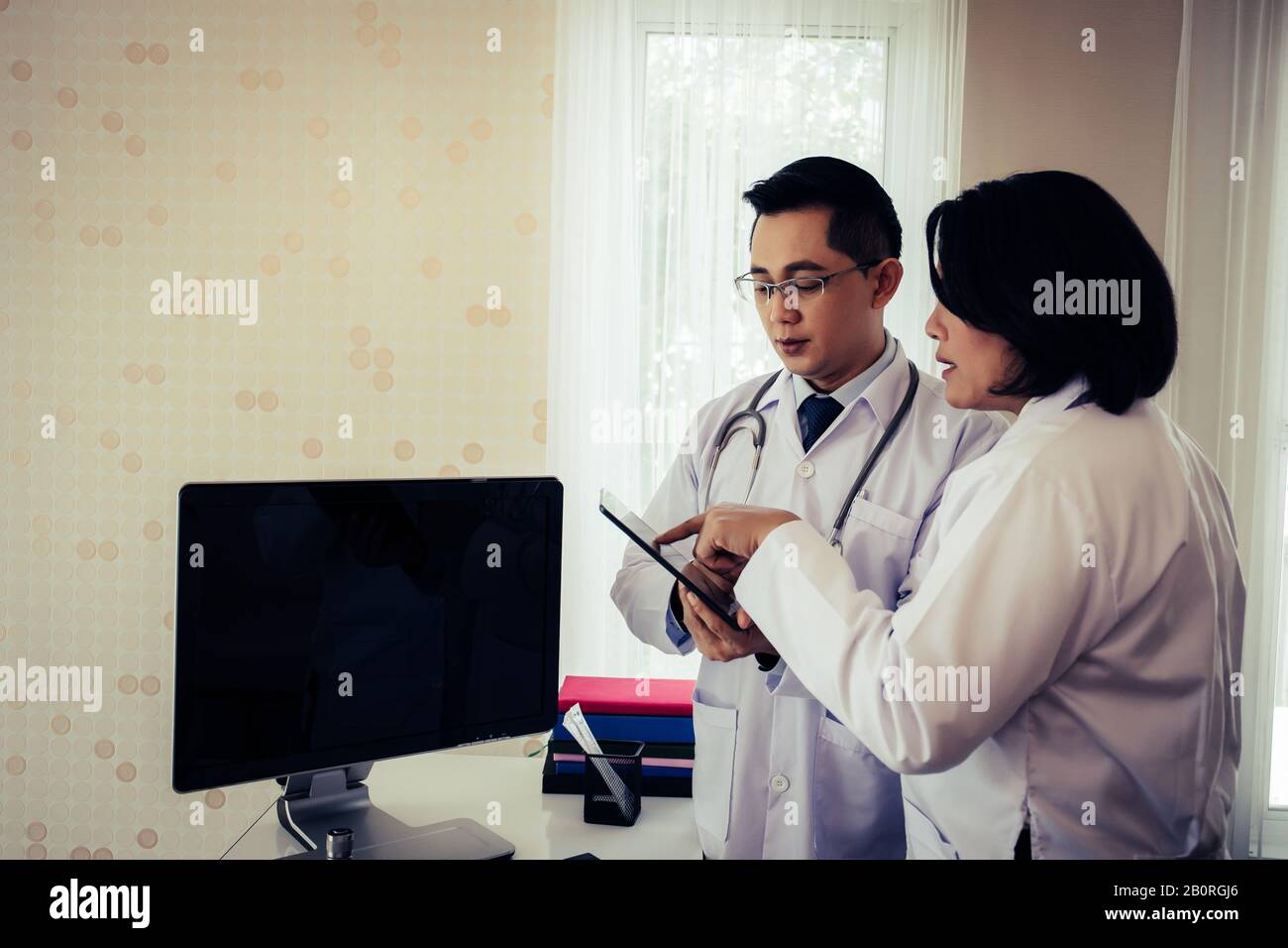 Two doctors discuss work. While watching through the tablet together in ...