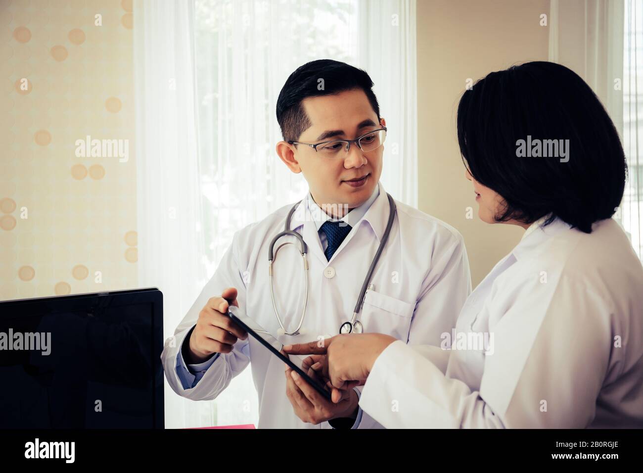Two doctors discuss work. While watching through the tablet together in ...