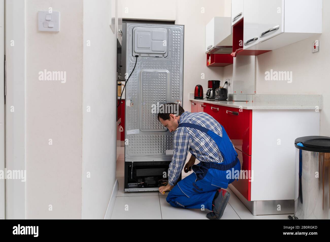 Young Male Serviceman Repairing Broken Refrigerator In Kitchen Stock ...