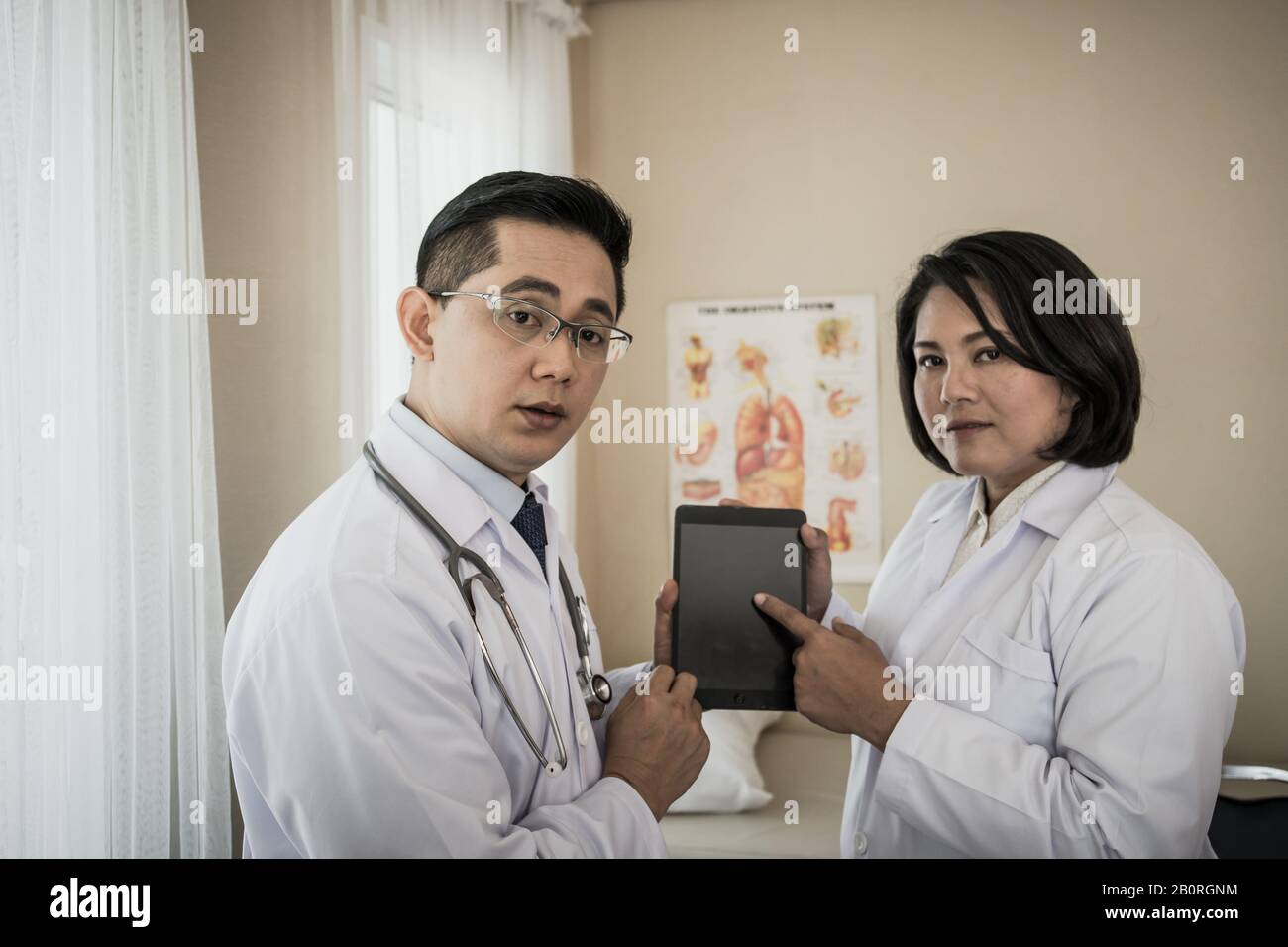 Two doctors discuss work. While watching through the tablet together in ...