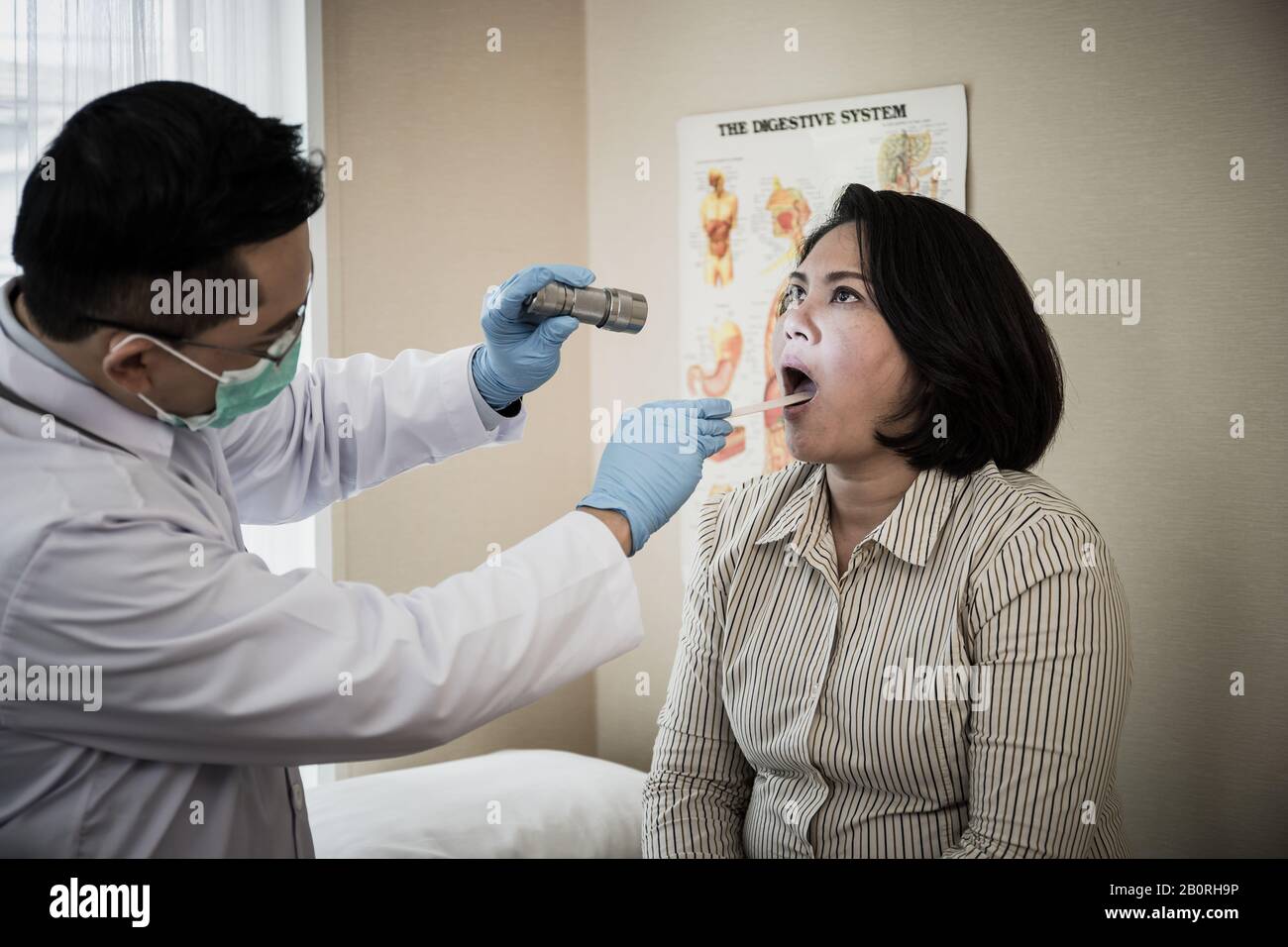 doctor in white uniform gown checkup patient's mouth with flashlight ...