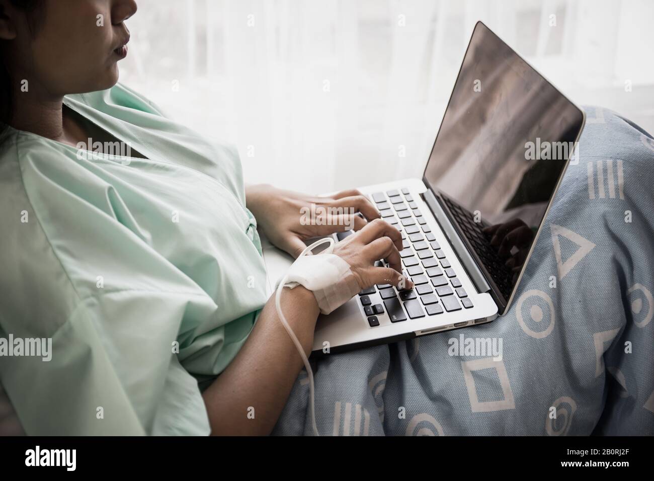 Sick woman works with laptop in hospital Stock Photo - Alamy