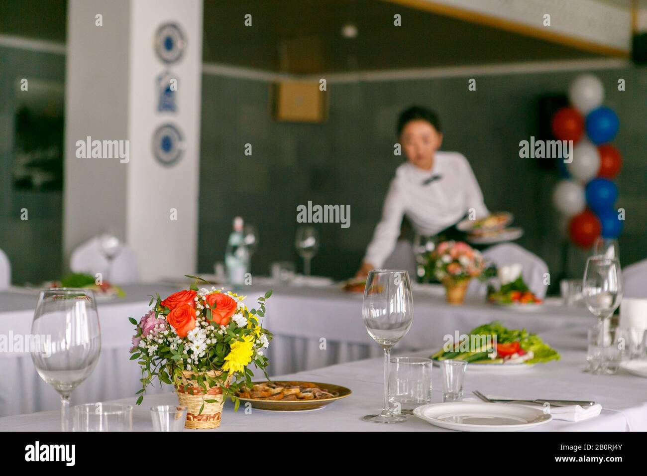 A close up of restaurant table set with the waitress serves the banquet ...