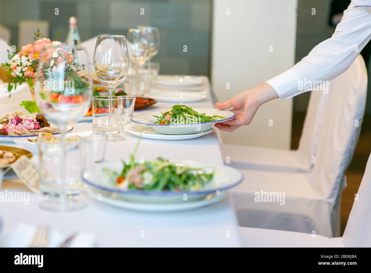 A close up of the waitress hand serves the green salad dish on the ...