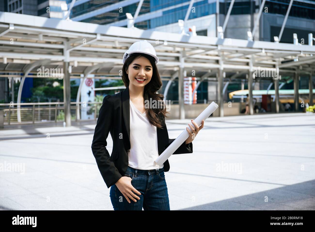 beautiful woman engineer holding paper plan is standing in front of an ...